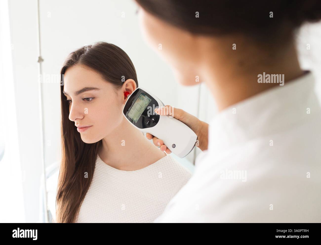 Woman having ear exam. Tympanometry measures the pressure in the middle ...