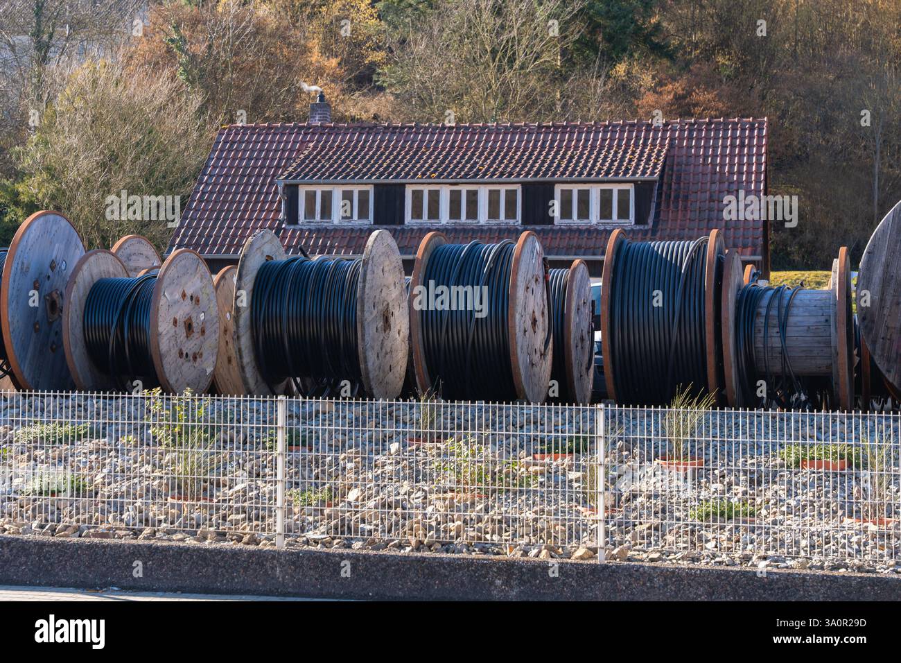 Wooden cable drums with black wire are stored in an open warehouse ...