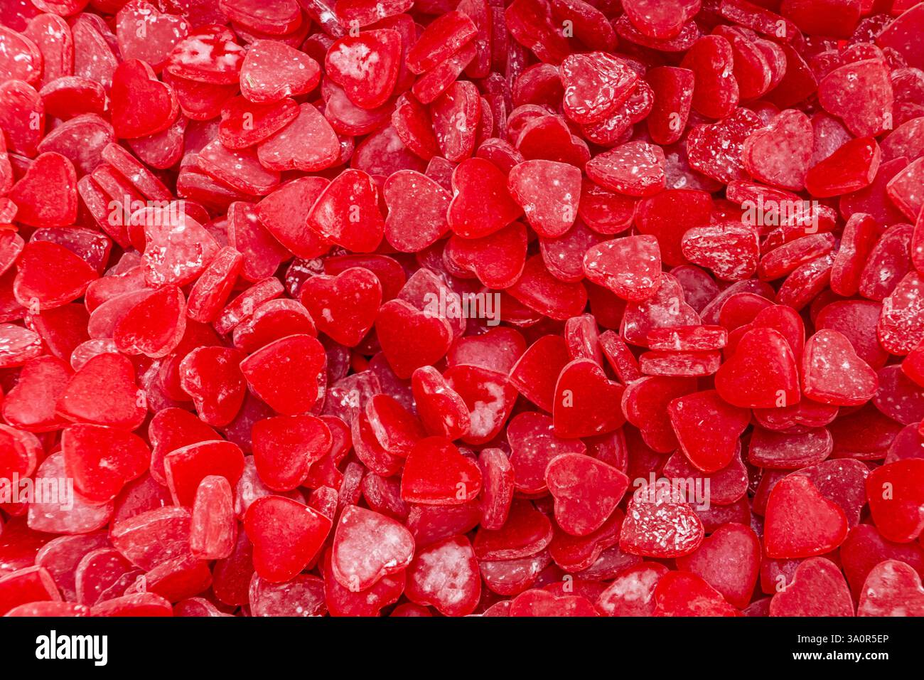 Textured surface of red heart gummy candies covered in sugar and starch ...