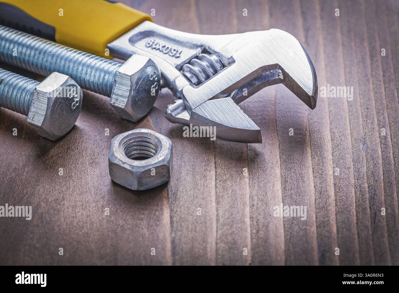 Composition of adjustable wrench bolts and nut on vintage wooden board ...
