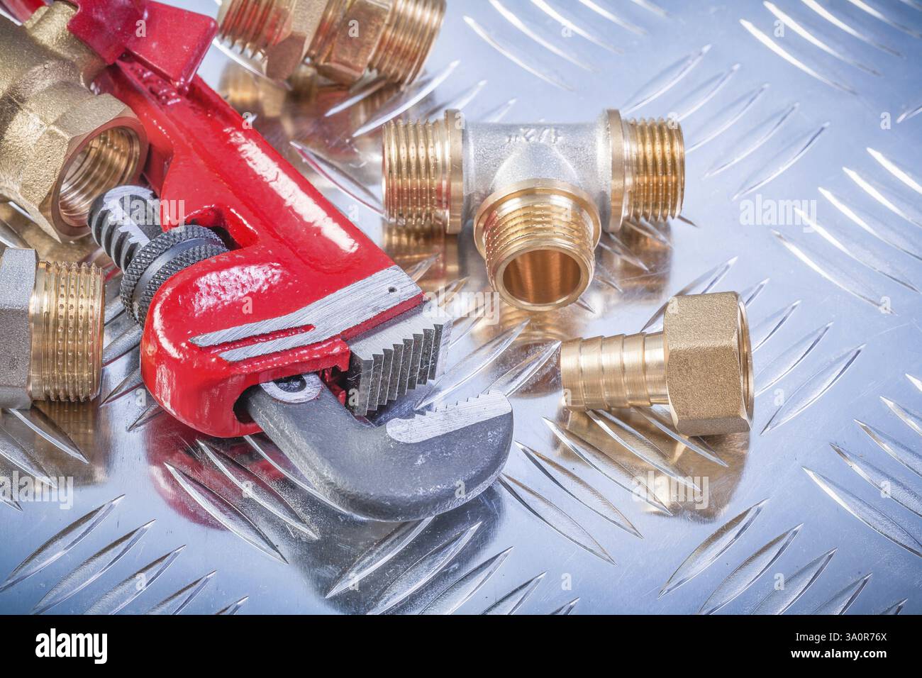 Collection of brass hardware on grooved metal background plumbing ...