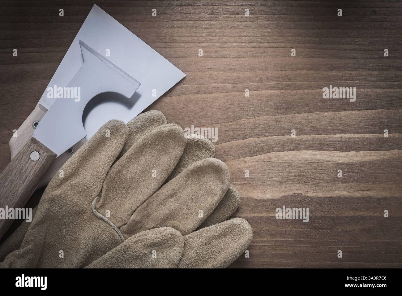 Construction safety gloves and putty knives on wooden background Stock ...