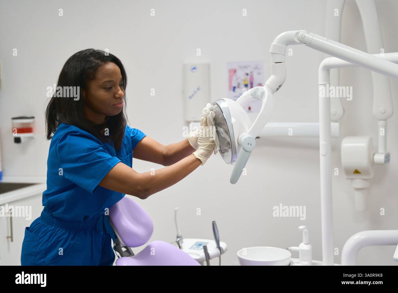 Dentist carefully cleaning the dental light with disinfectant, ensuring ...