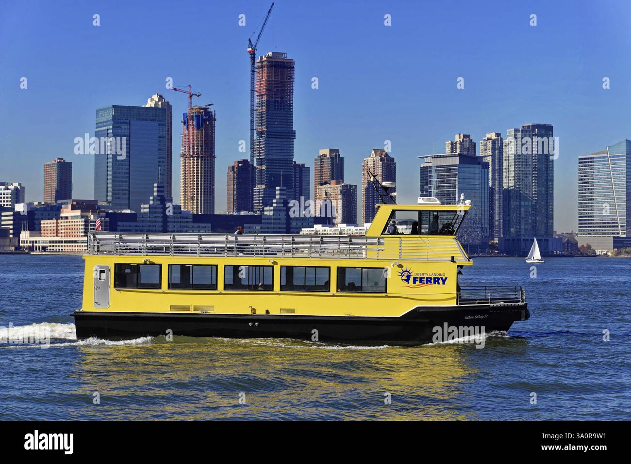 A yellow ferry sails in front of a modern skyscraper skyline on the ...