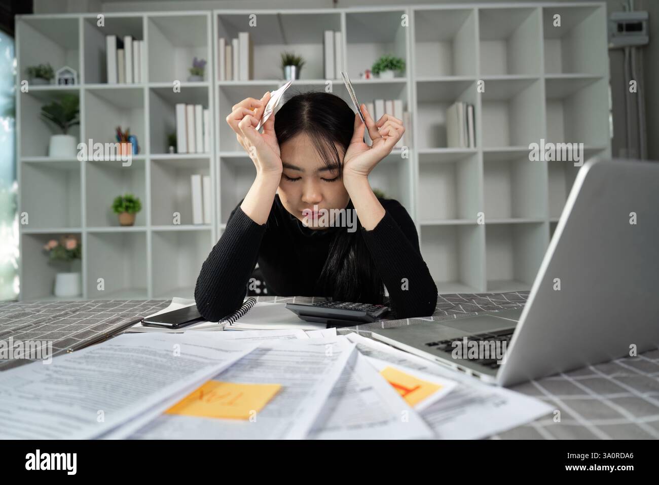 Tax stress. An individual overwhelmed by tax preparation at a cluttered ...