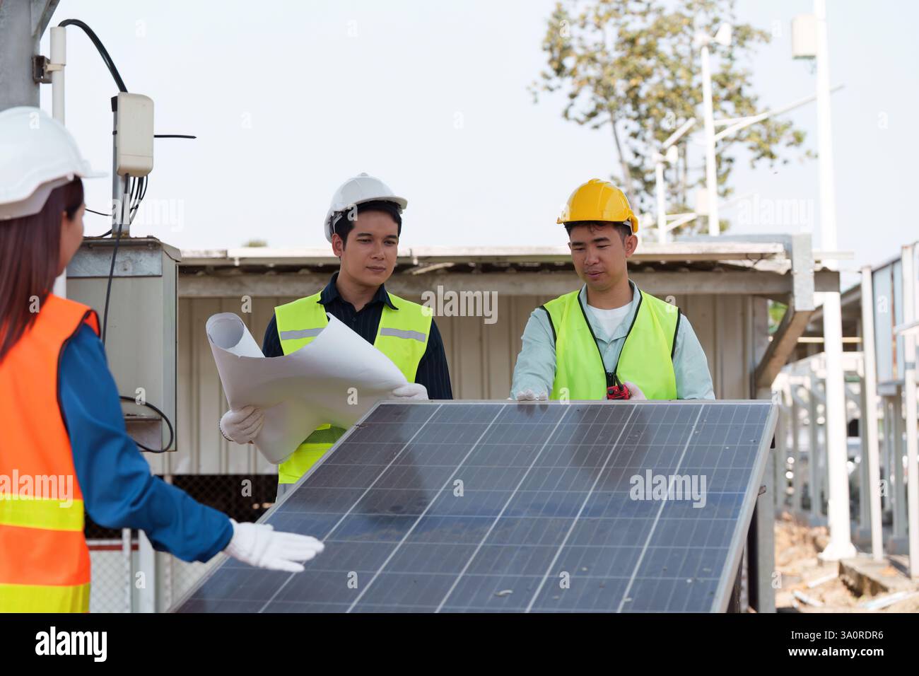 Collaborative planning for solar technology. Engineers surveying solar panels and discussing ...
