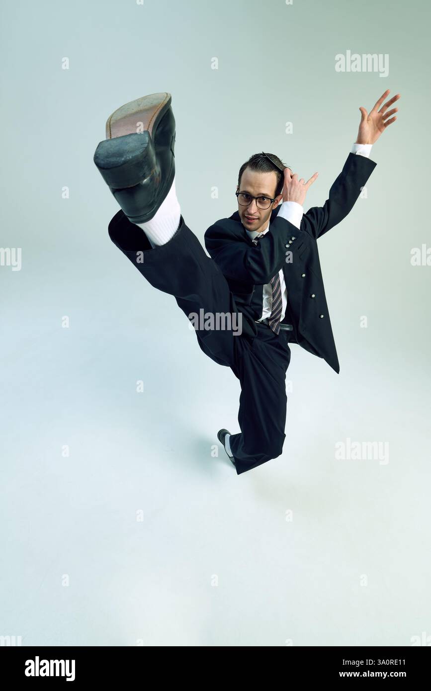 Young businessman lifting leg high while striking confident pose ...