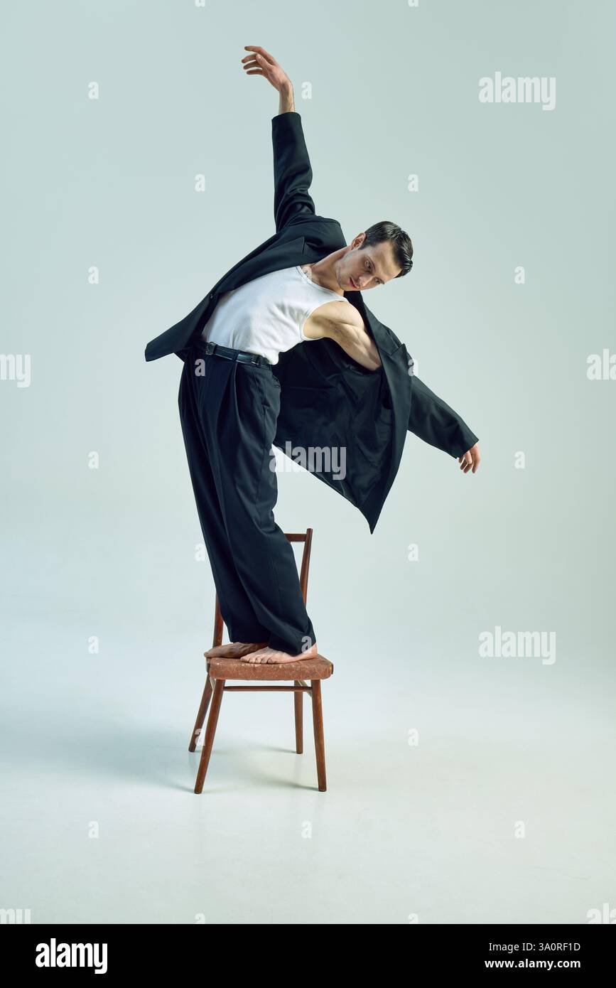 Barefoot man balancing on wooden chair in dramatic business stance ...