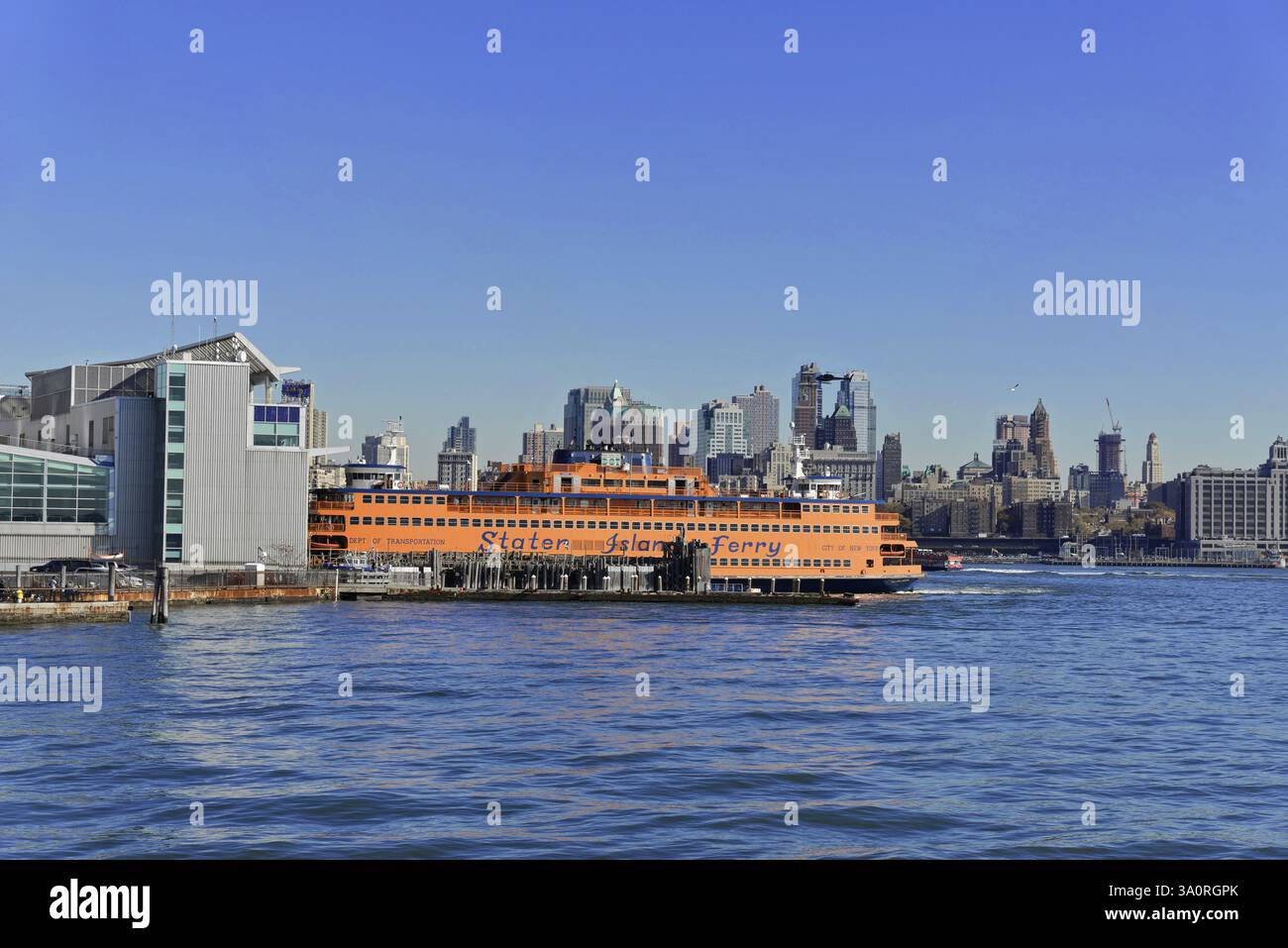 The orange-coloured Staten Island Ferry in front of an urban skyline ...
