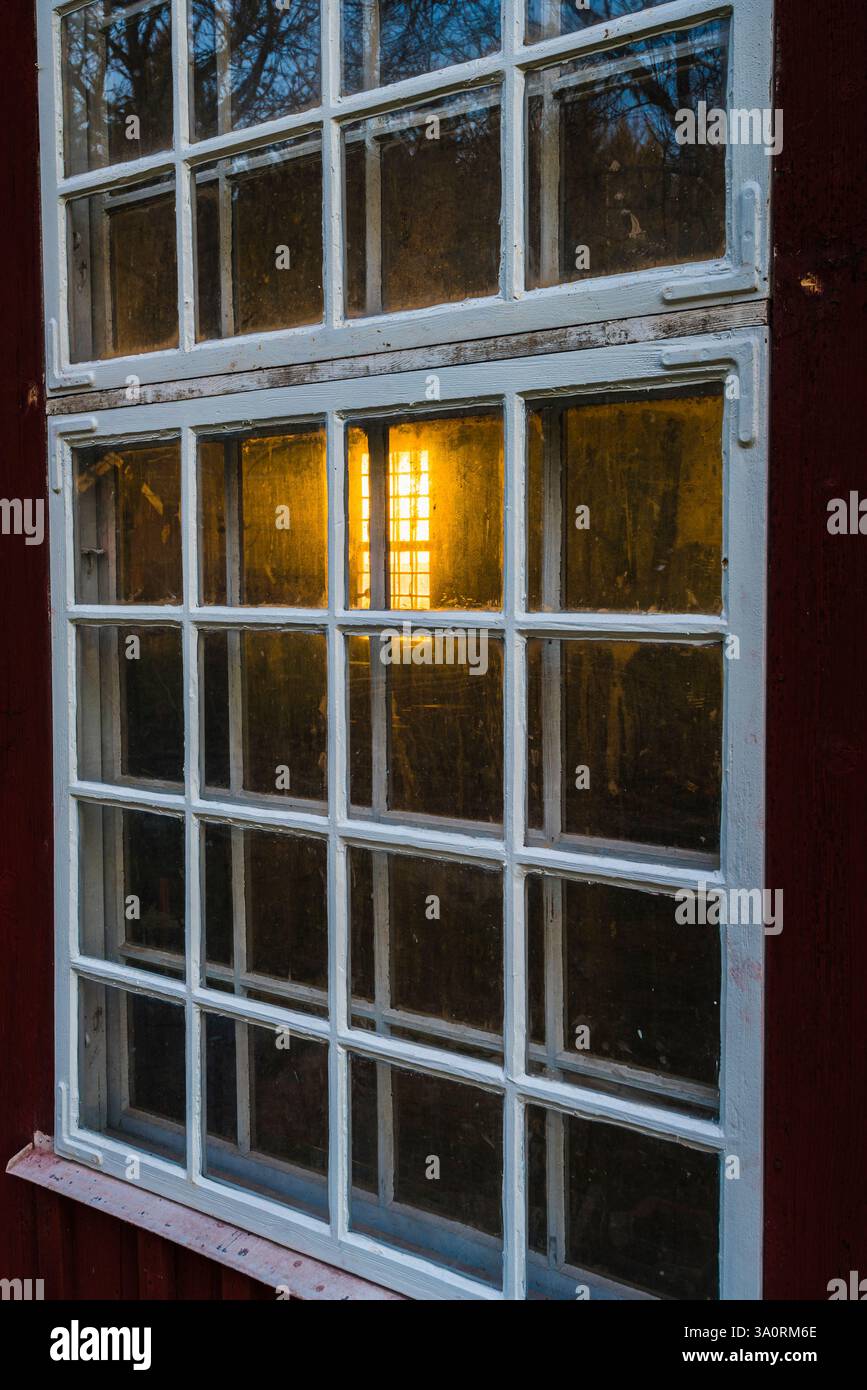 A warm light radiates through a rustic window with many panes ...