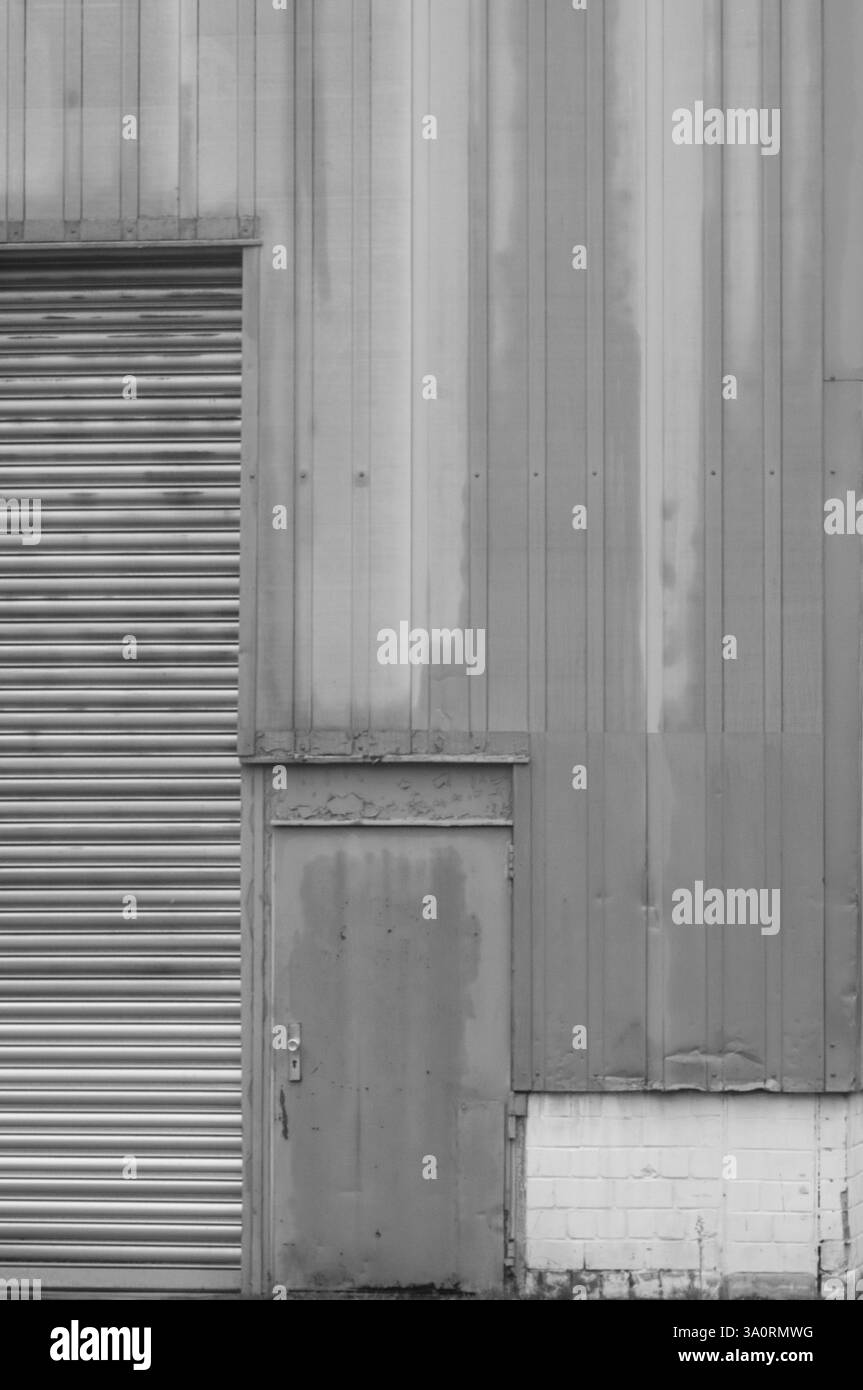 Grey industrial building exterior featuring a closed roller shutter ...