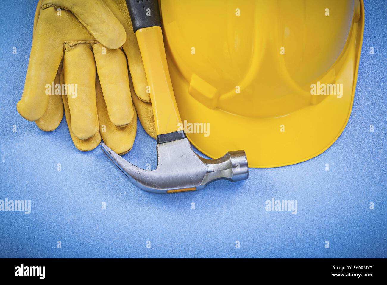 Composition of claw hammer safety gloves hard hat on blue background ...