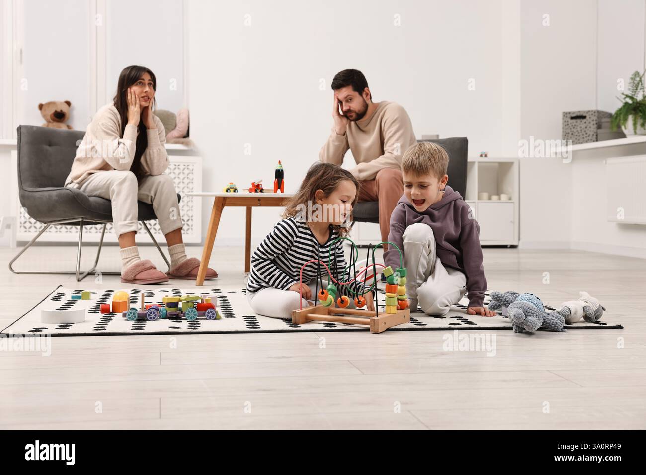 Hyperactive children playing and their overwhelmed parents at home ...