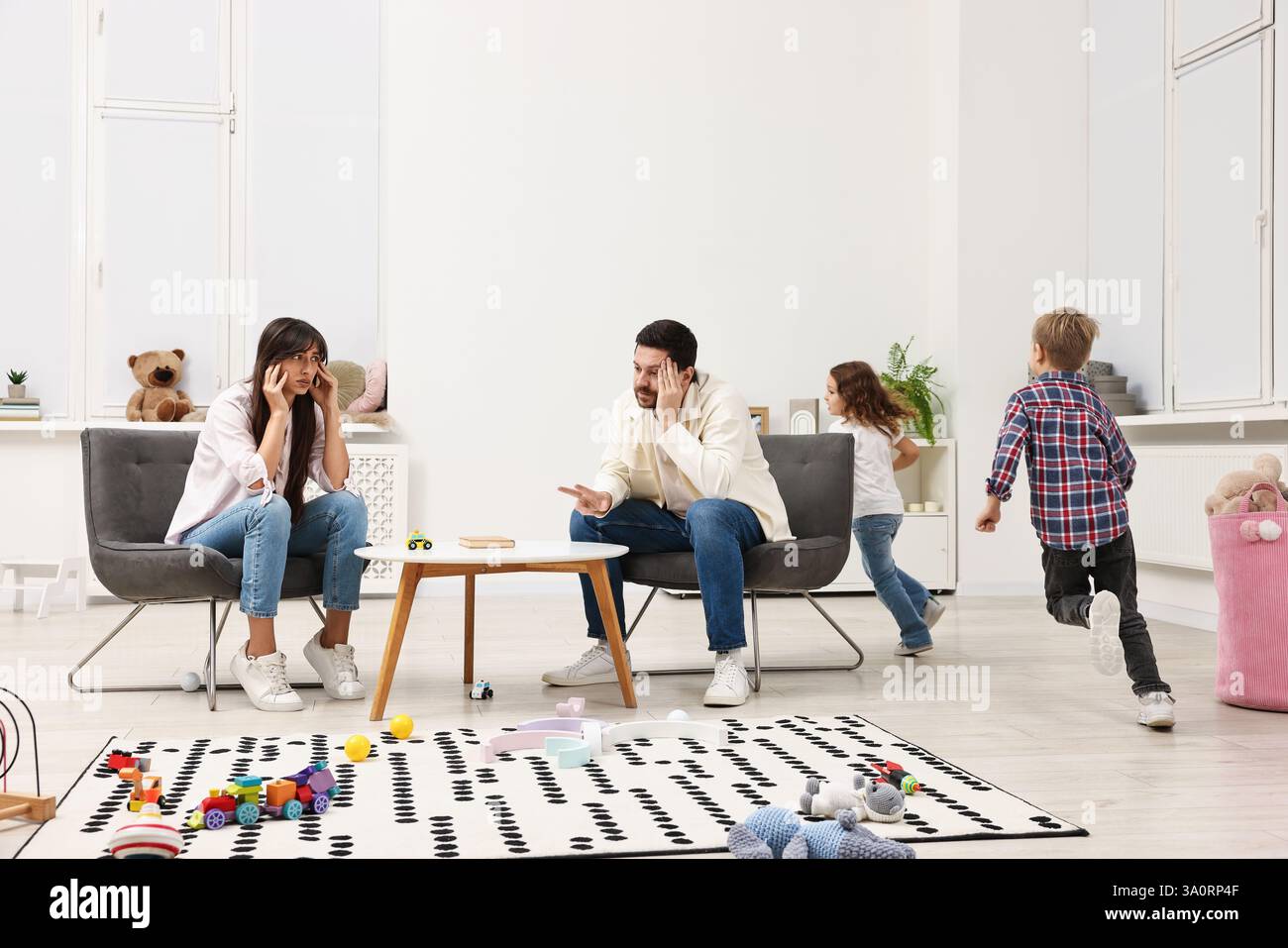 Hyperactive children playing and their overwhelmed parents at home ...