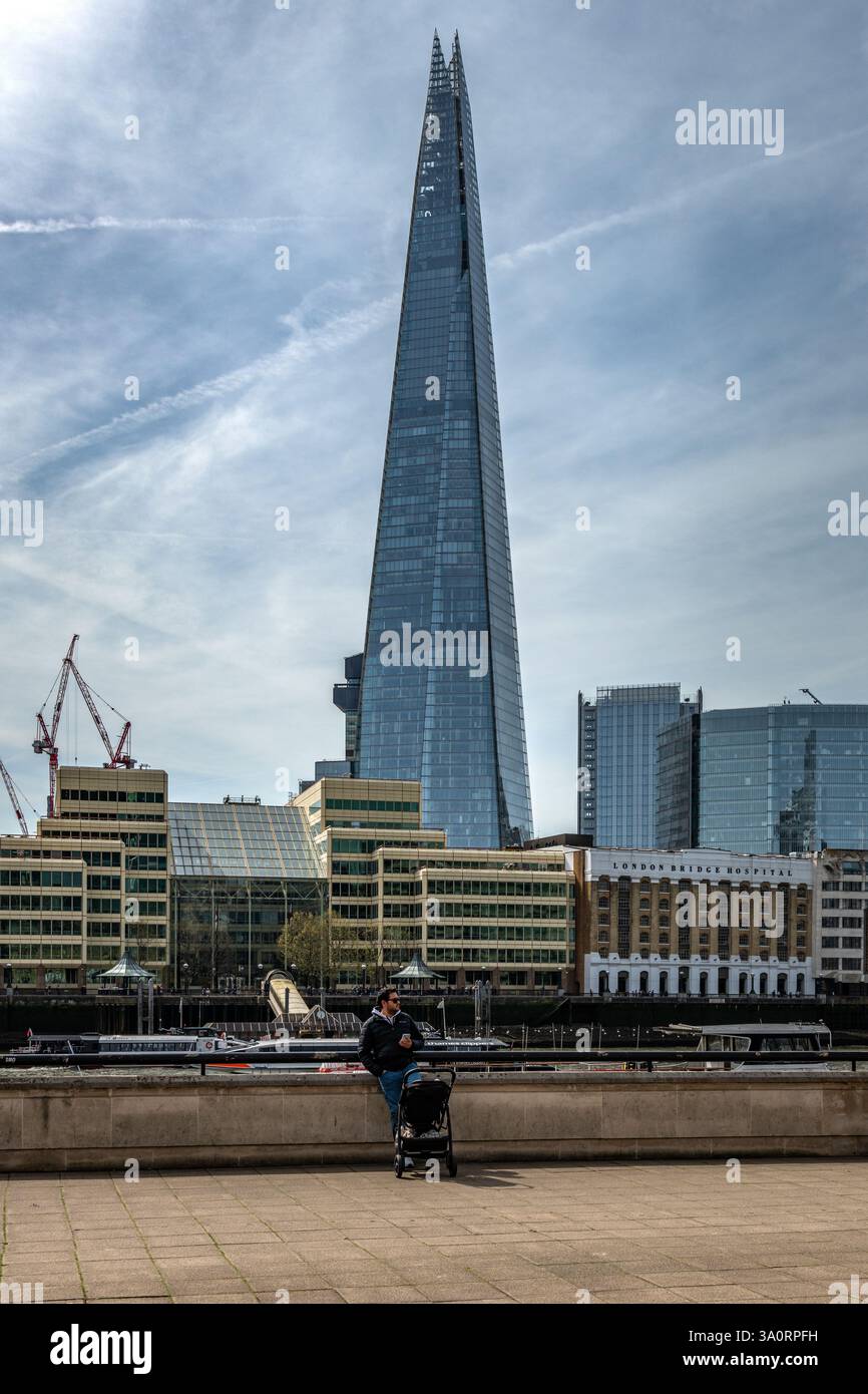A man walking his baby along the banks of the Thames with the shard ...