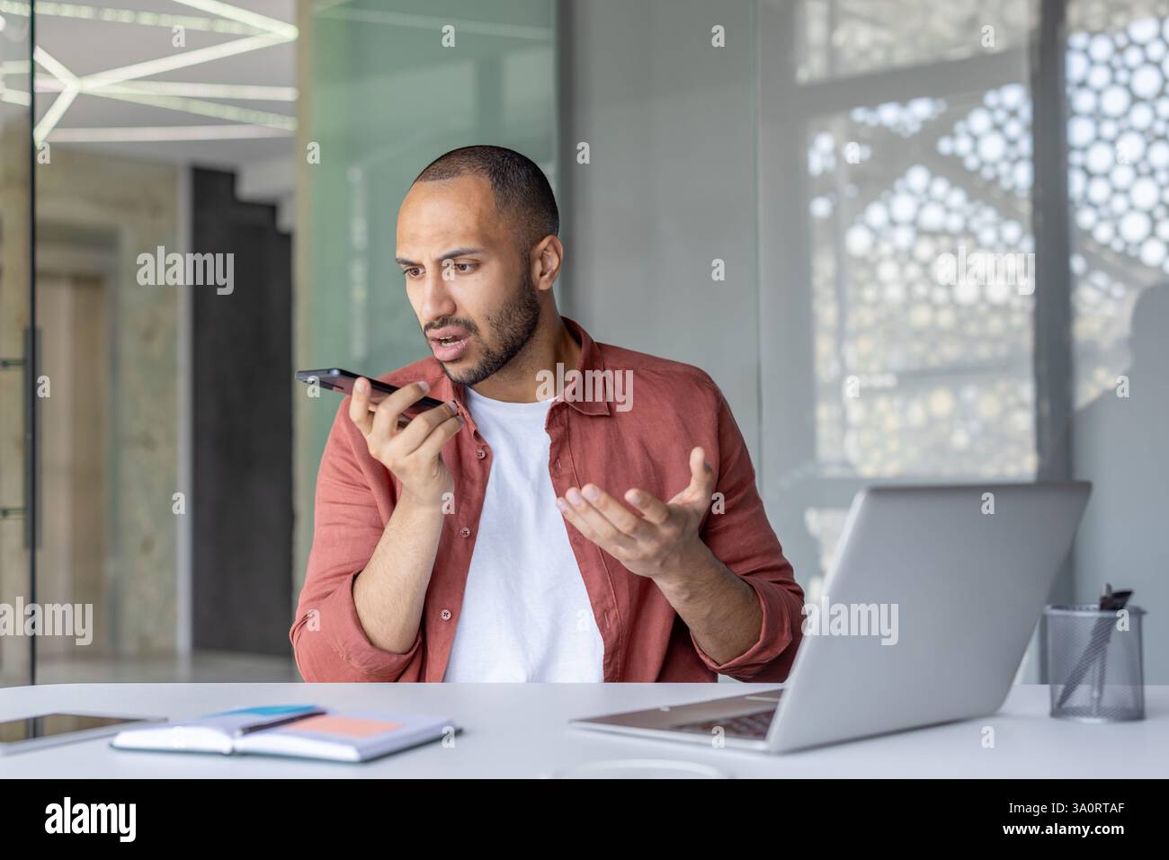 Worried businessman using voice assistant on his smartphone while ...
