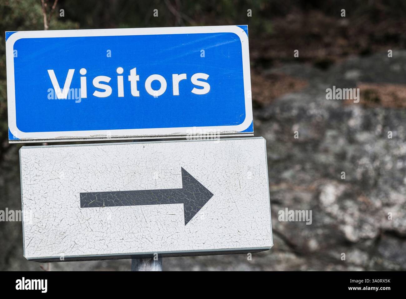 A clear blue and white sign indicating the direction for visitors. It ...