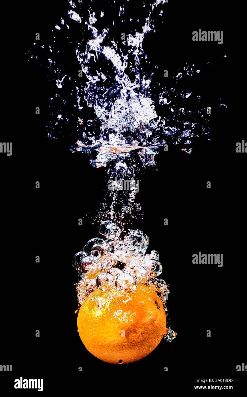 The moment an orange is dipped into water, creating a stunning splash ...