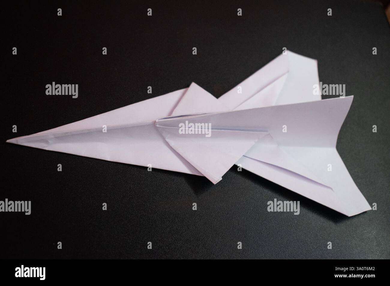 A sleek, handmade paper origami fighter jet with sharp angles and wings ...