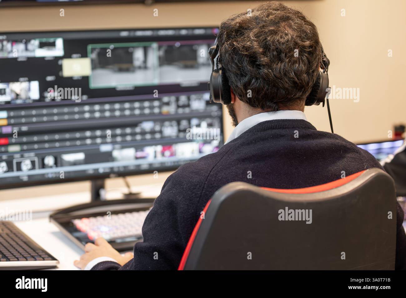 A television director in a broadcast control room, actively guiding a ...