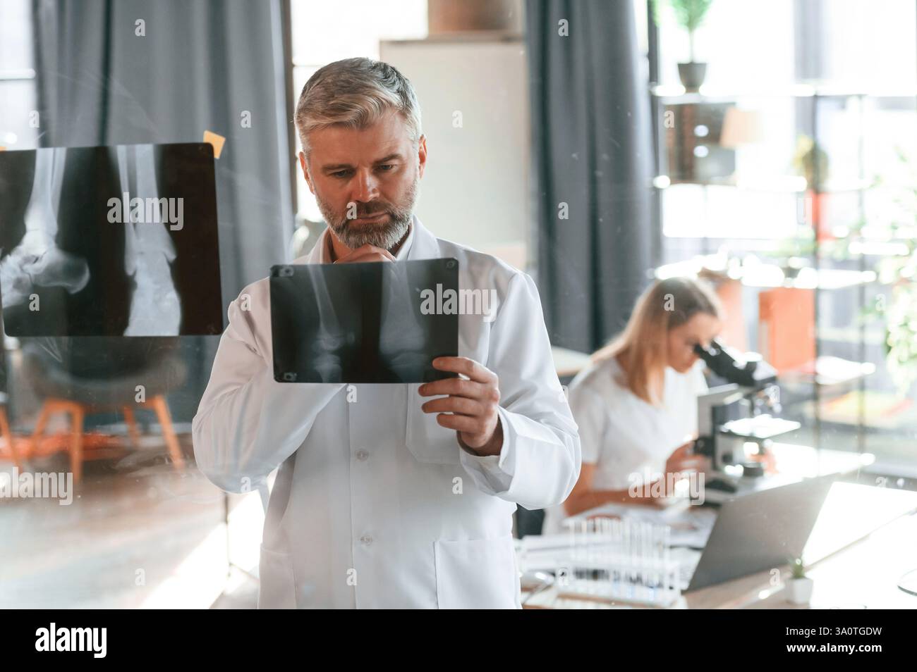Man is holding and watching at x-ray. Two clinic workers are indoors together Stock Photo - Alamy