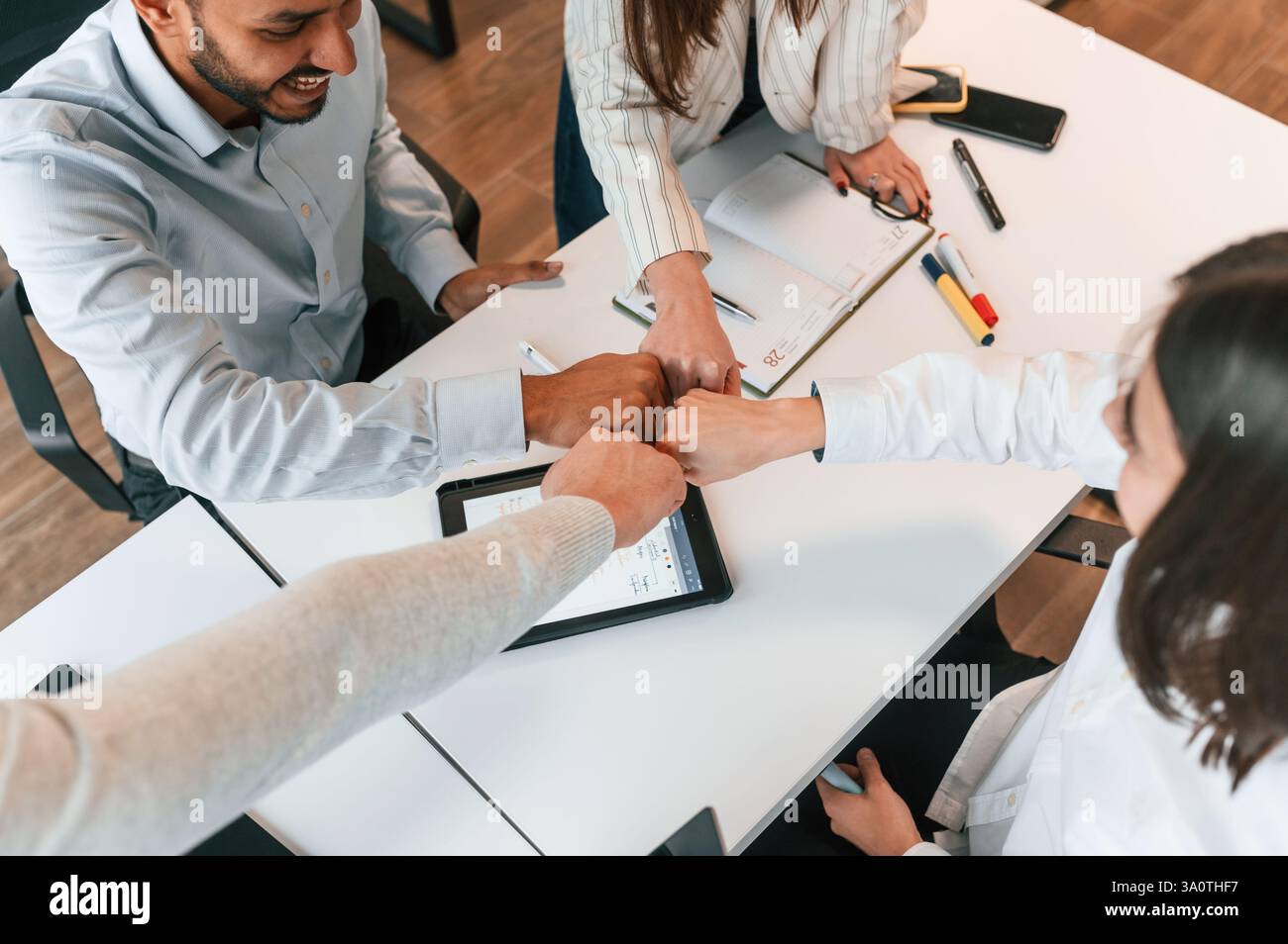 Success, making hand gestures. Four people are working in the office ...