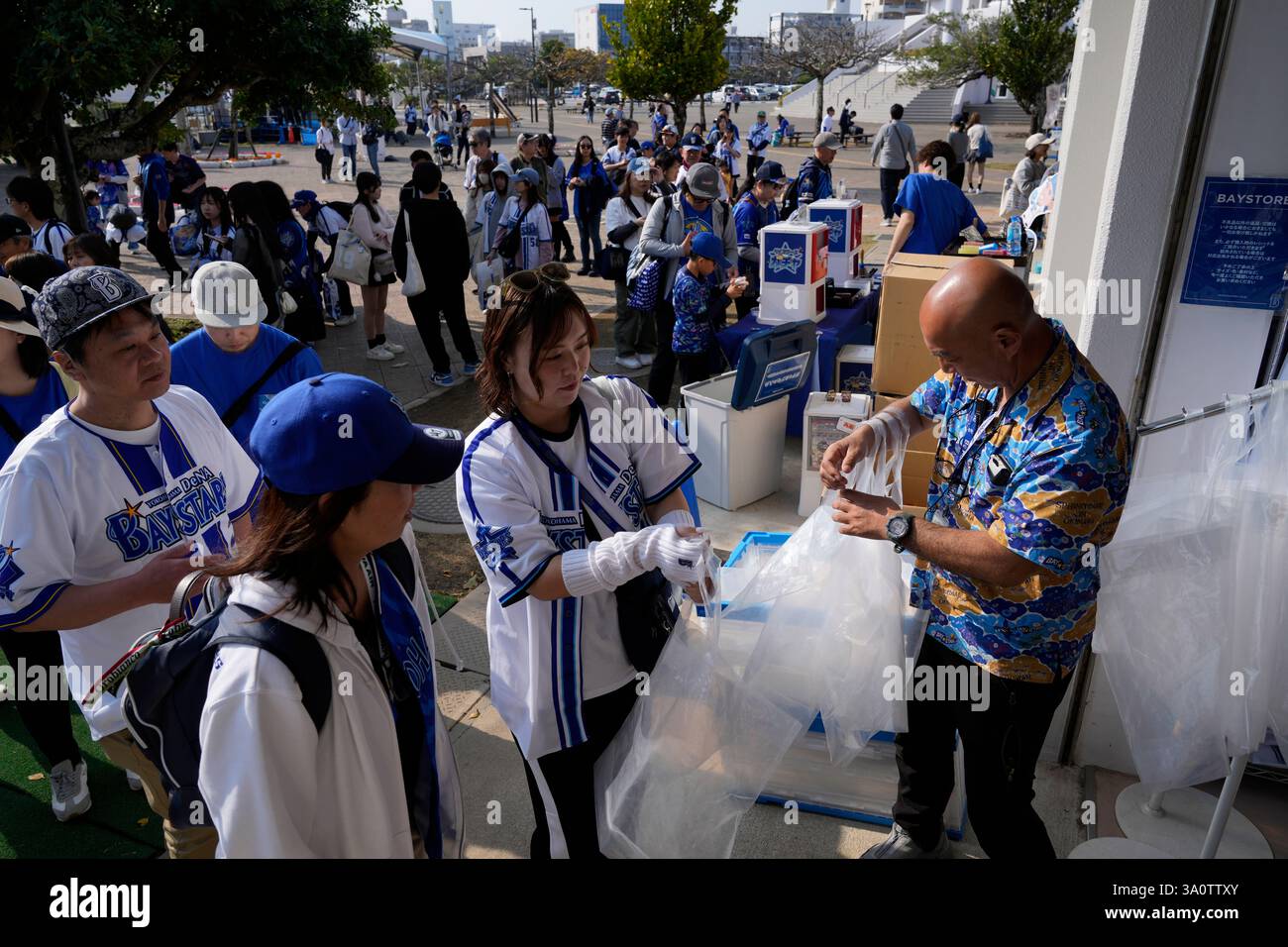 Baseball fans of the Yokohama DeNA BayStars wait in line to go inside ...