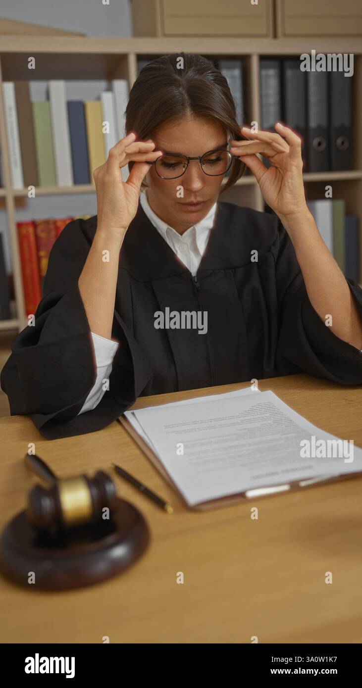 Hispanic woman judge adjusting glasses while reading a legal document ...