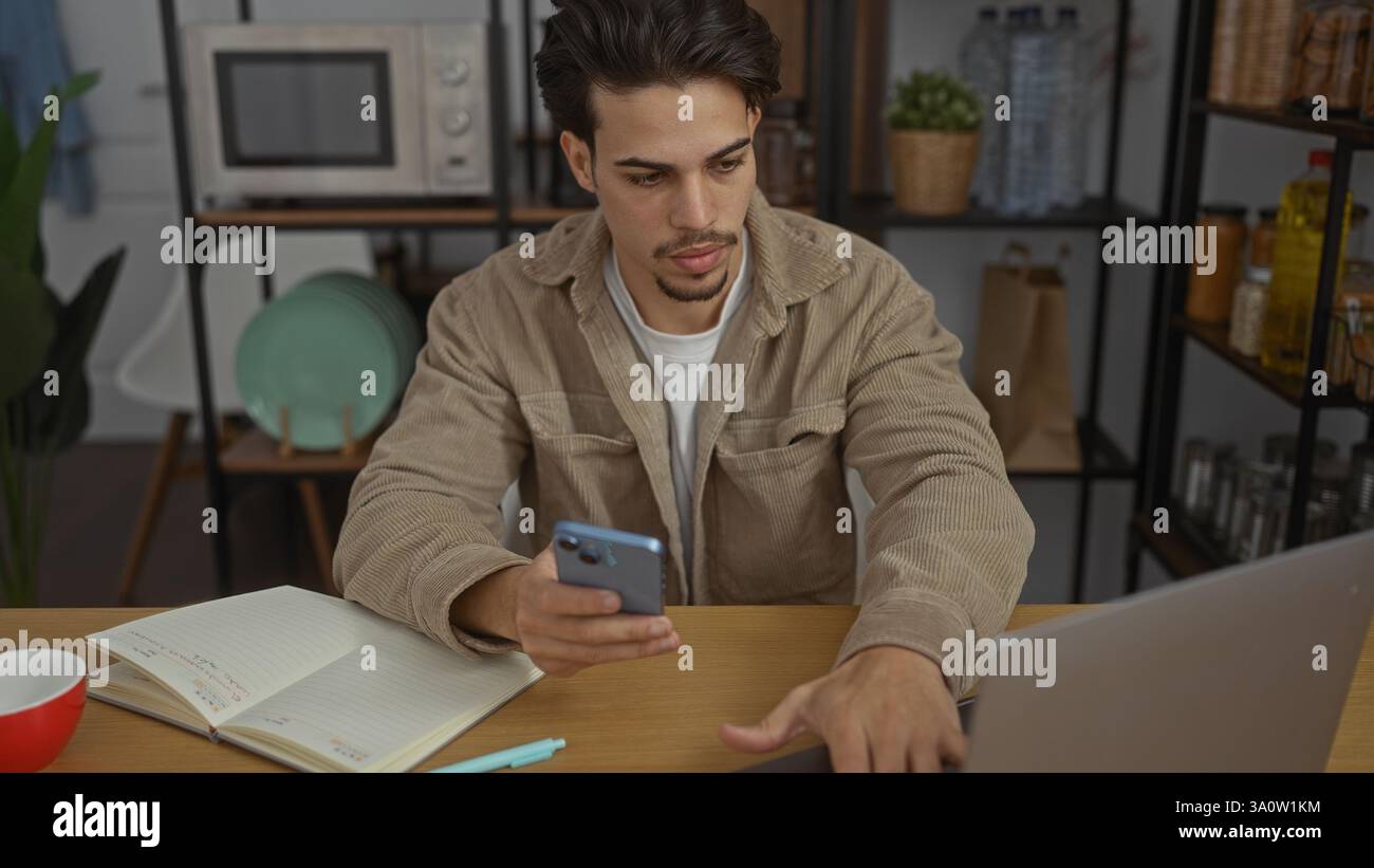 Young hispanic man working indoors with smartphone and laptop in office ...