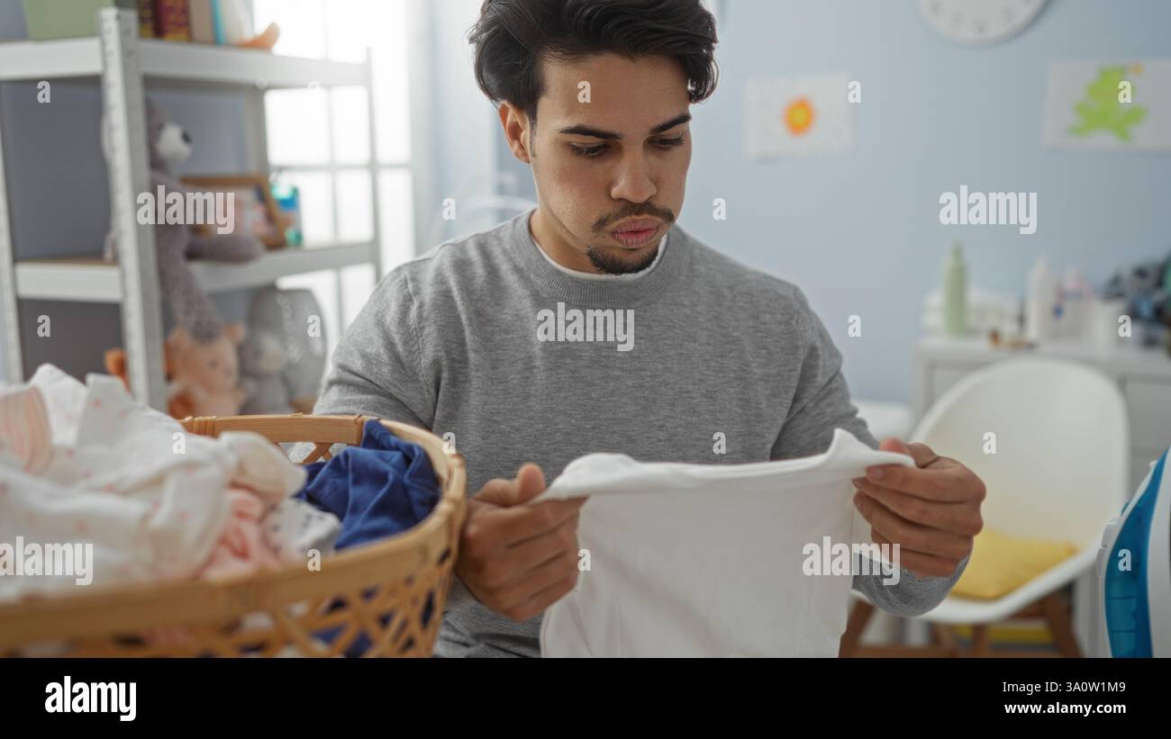 Young hispanic man indoors in a laundry room sorting clean clothes ...