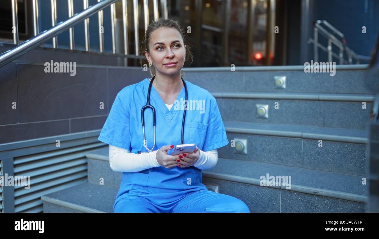 Nurse in blue scrubs sitting outdoors on city steps with short hair ...