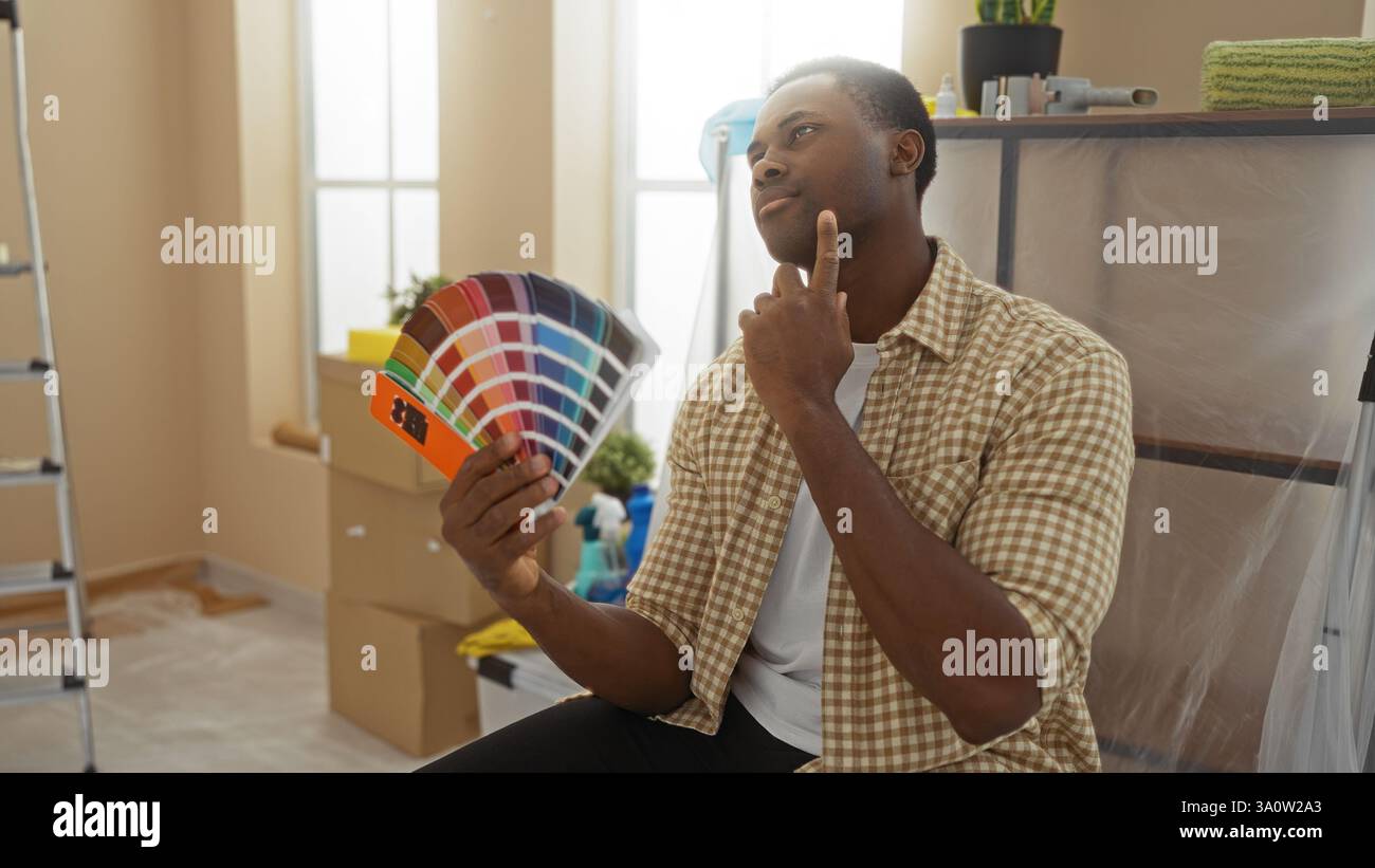 Young man in living room thoughtfully examines color palette for new ...