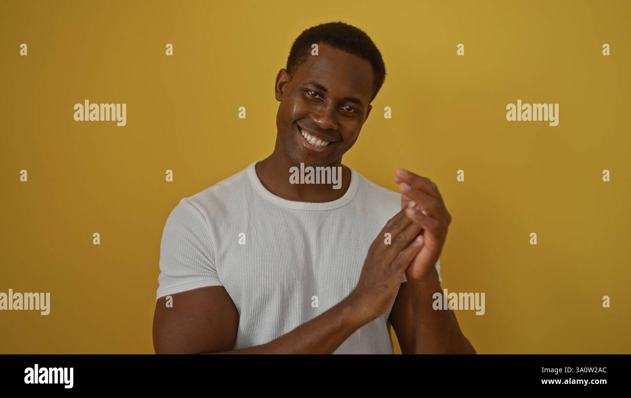 Young man clapping with a bright smile over an isolated yellow ...