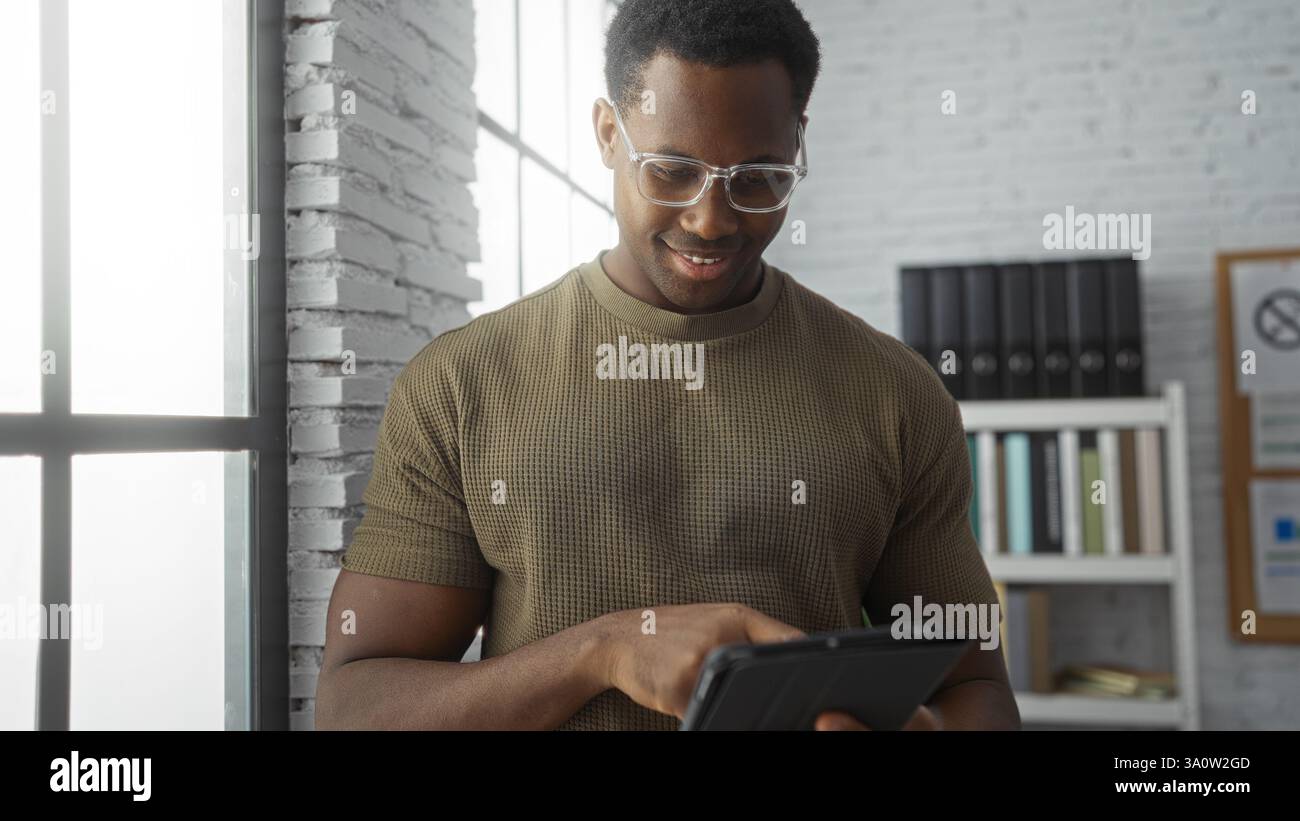 Young, handsome, african american man in an office room using a tablet ...