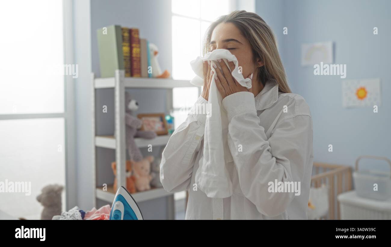 Blonde woman in a laundry room smelling laundry with an iron ...