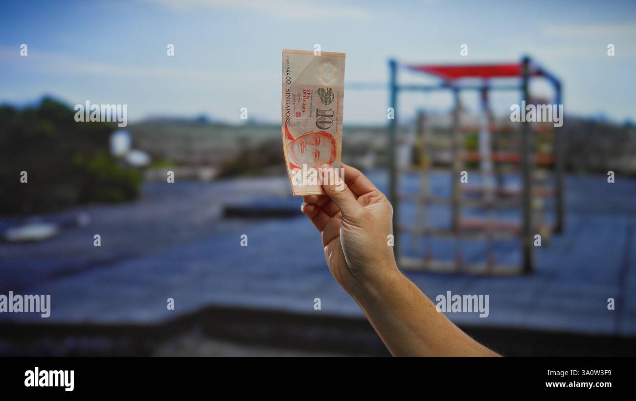 Hand holding singapore banknote outdoors in a park setting, blending ...