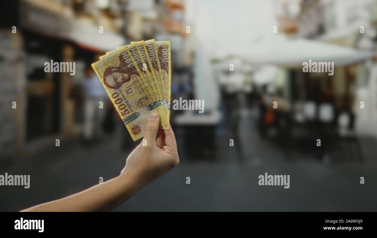 Hand holding hungarian forint banknotes on a bustling city street ...