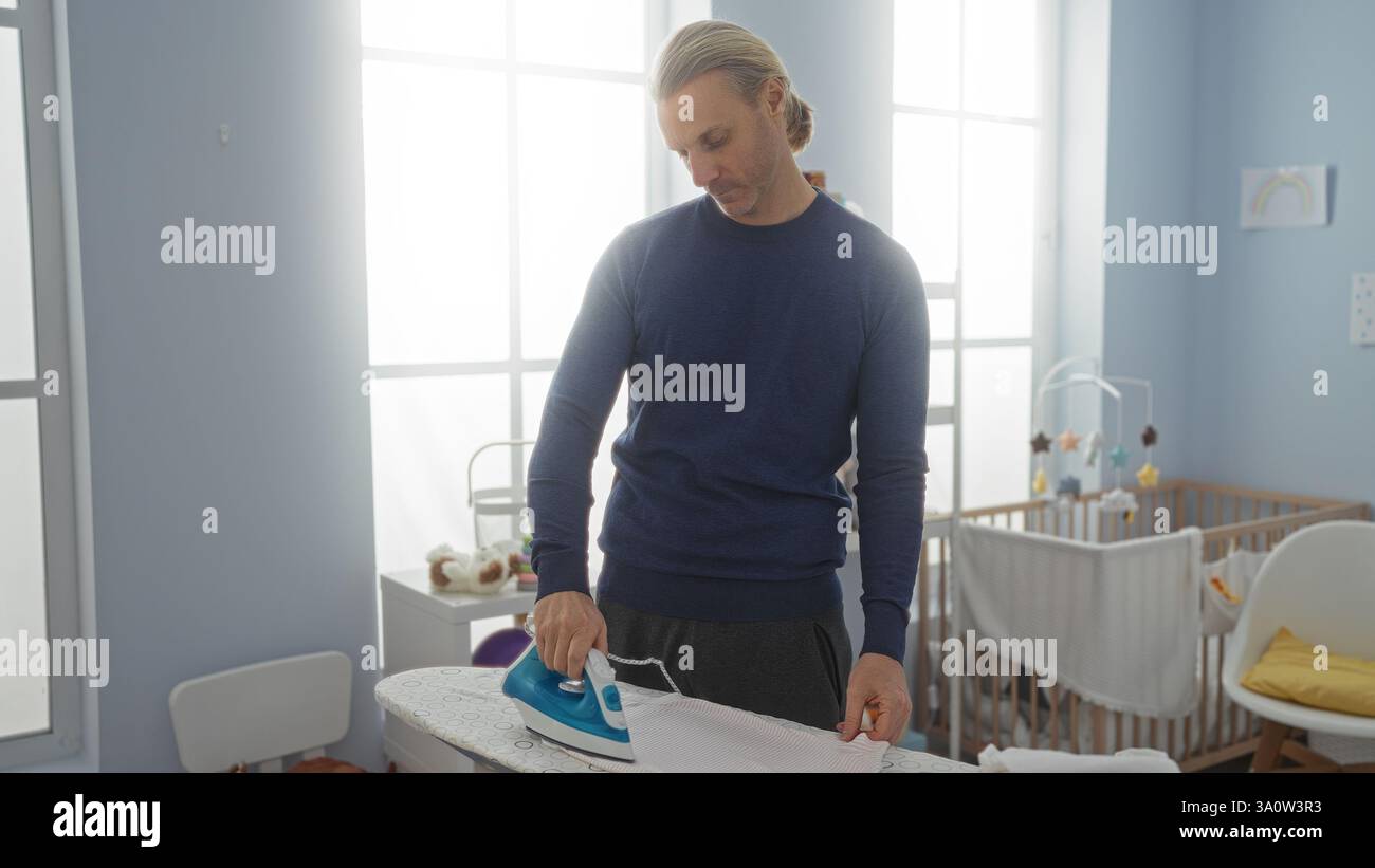 Middle-aged man ironing clothes in a bright laundry room, showcasing ...
