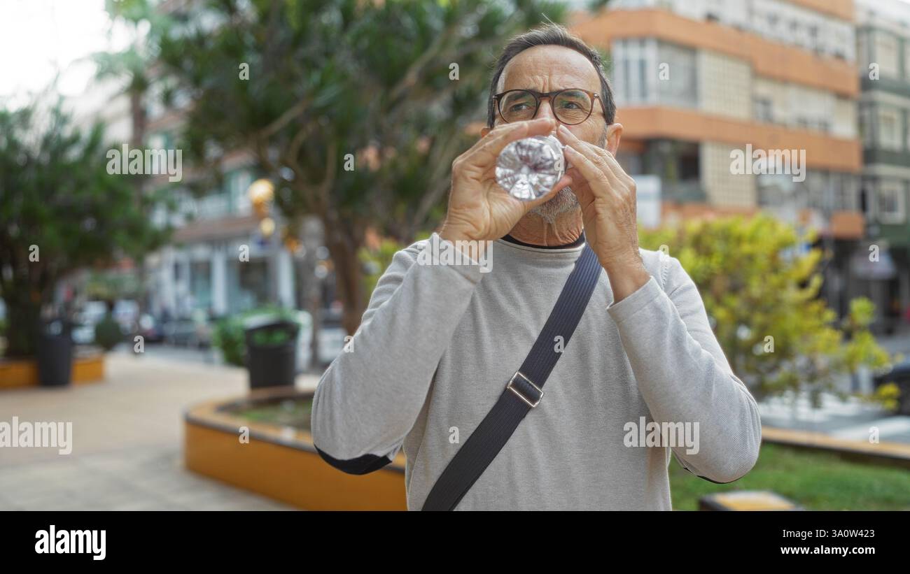 Man drinking water in a vibrant urban park setting, surrounded by lush ...