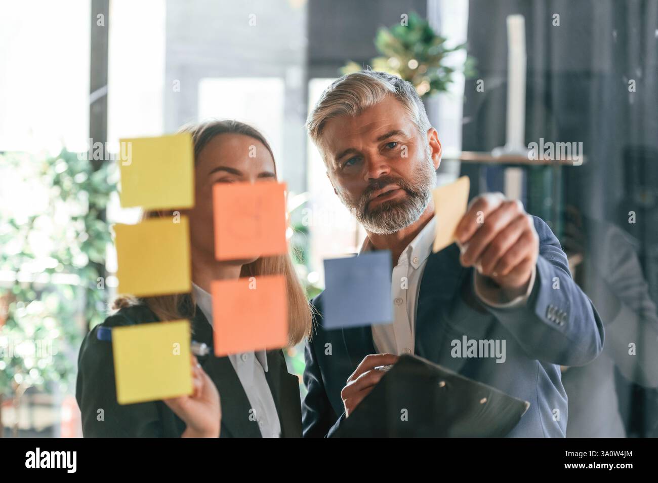 Creating the plan. Putting stickers on the glass. Business people are ...