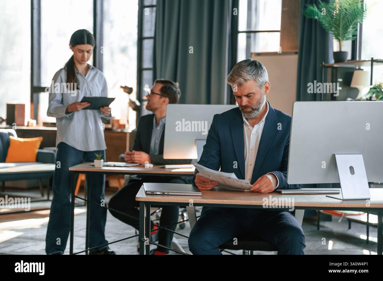 Three people are busy in the office. Group of employees are working ...