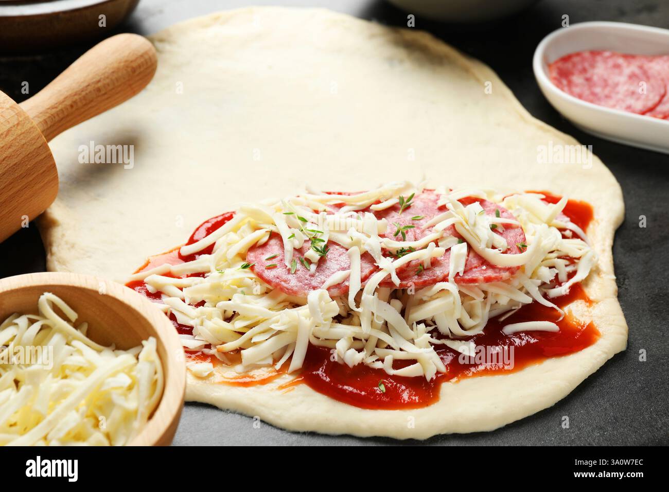 Making calzone pizza. Dough with sauce and stuffing on grey table ...