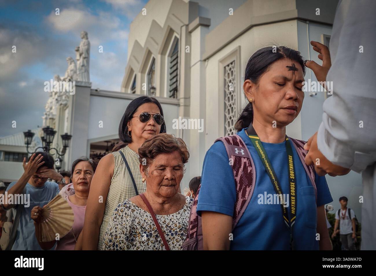 Catholic believers line up to receive ash marks in the shape of a cross ...