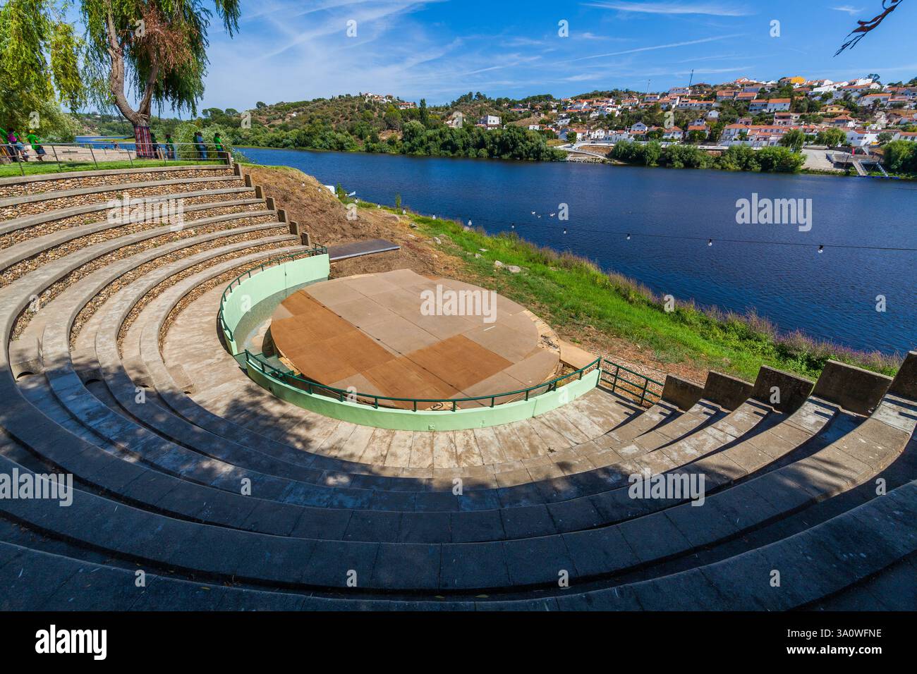 An open-air amphitheater with stone seating overlooking a calm river ...