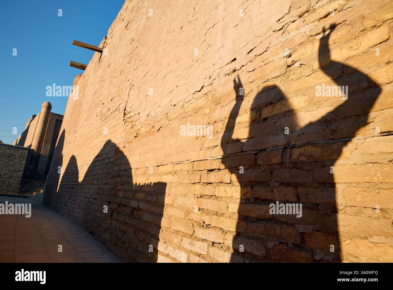 Shadow of eastern woman in ethnic dress on the old facade of historic budling is dancing ...