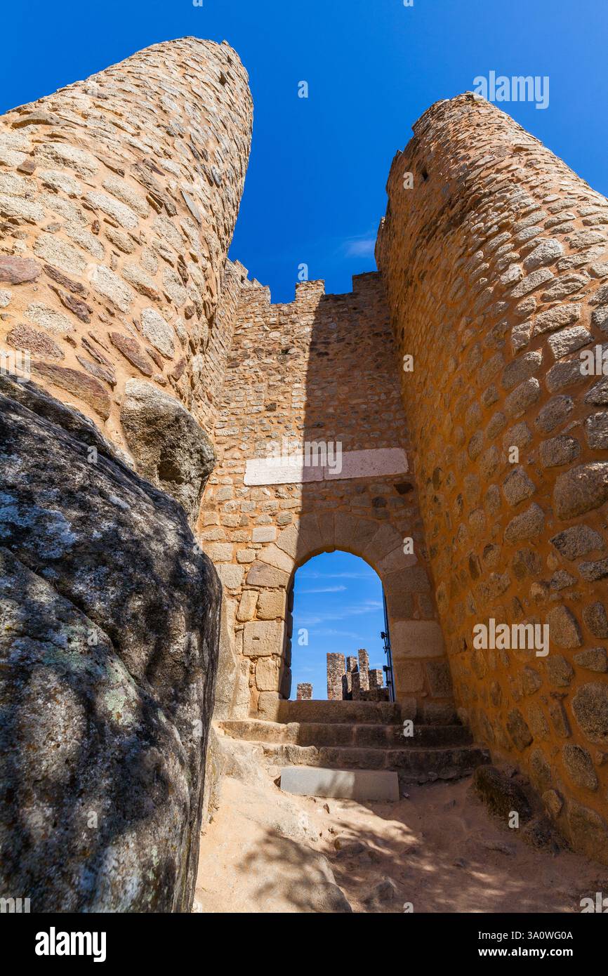 stone archway and towering castle walls set against a bright blue sky ...