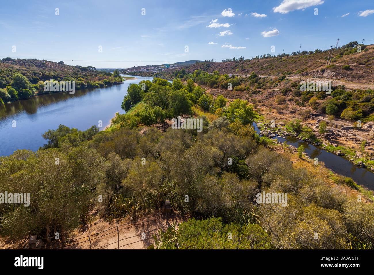 meandering river surrounded by lush trees and arid hillside terrain ...