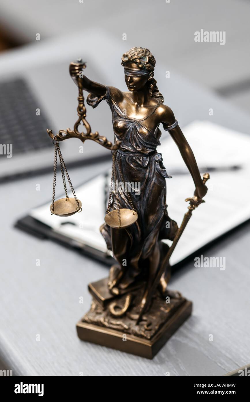 A lawyer sitting at their desk with the Statue of Themis, goddess of ...