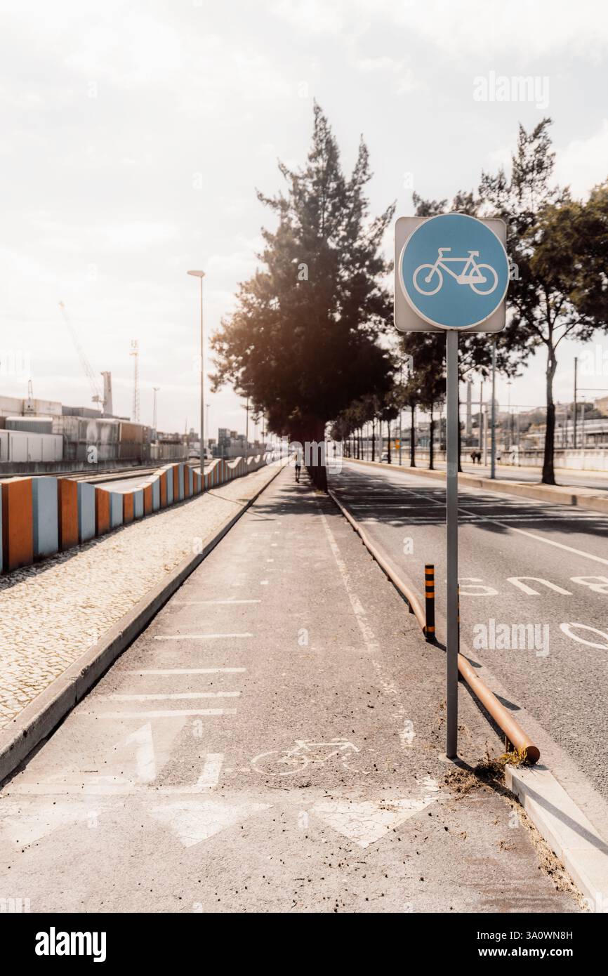 A dedicated bicycle lane with a blue cycling sign stands beside an ...
