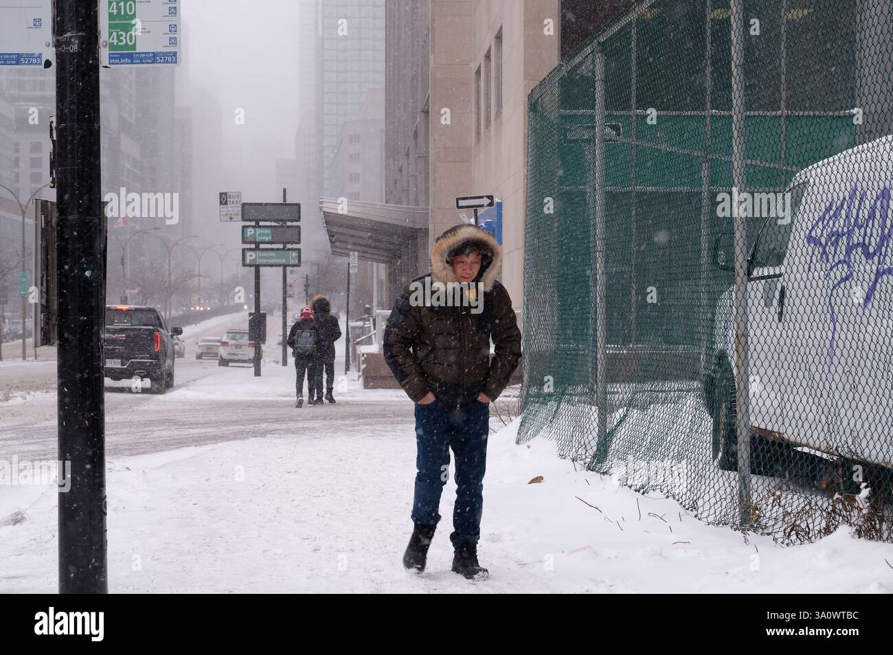 Hard winter day as pedestrians navigate icy sidewalks during a snow ...